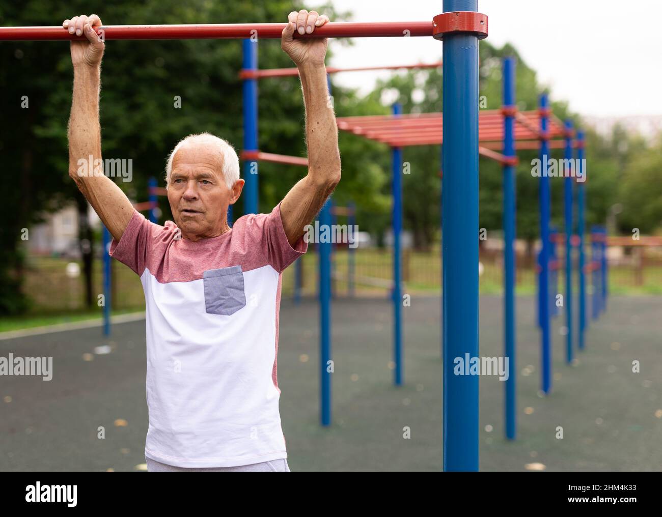Elderly man hanging from pullup bar and doing pull-ups Stock Photo - Alamy