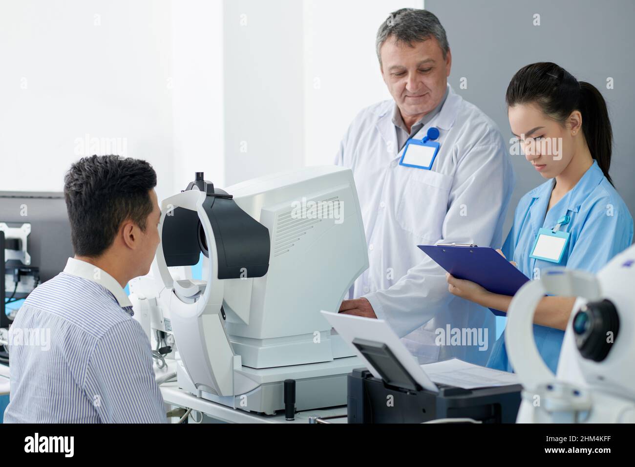 Optometrist telling details of patients examination to nurse who is ...