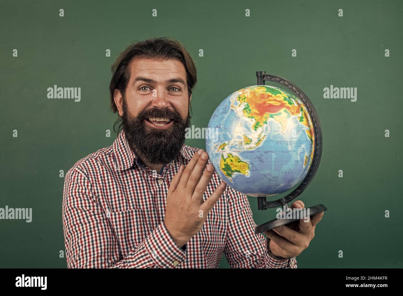 happy bearded man in checkered shirt looking at geographic globe ...