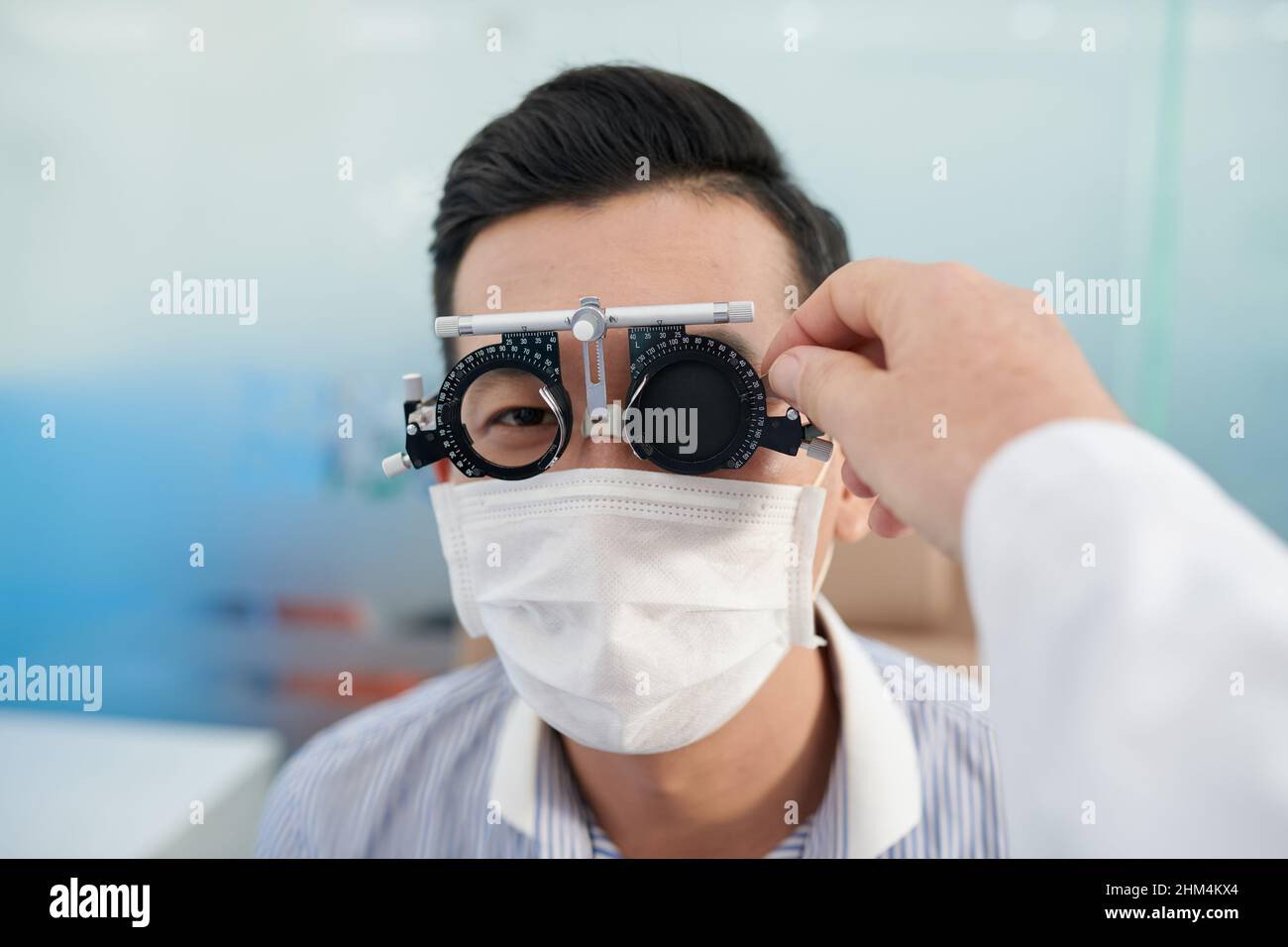 Ophthalmologist helping patient to select glasses, he is covering one ...