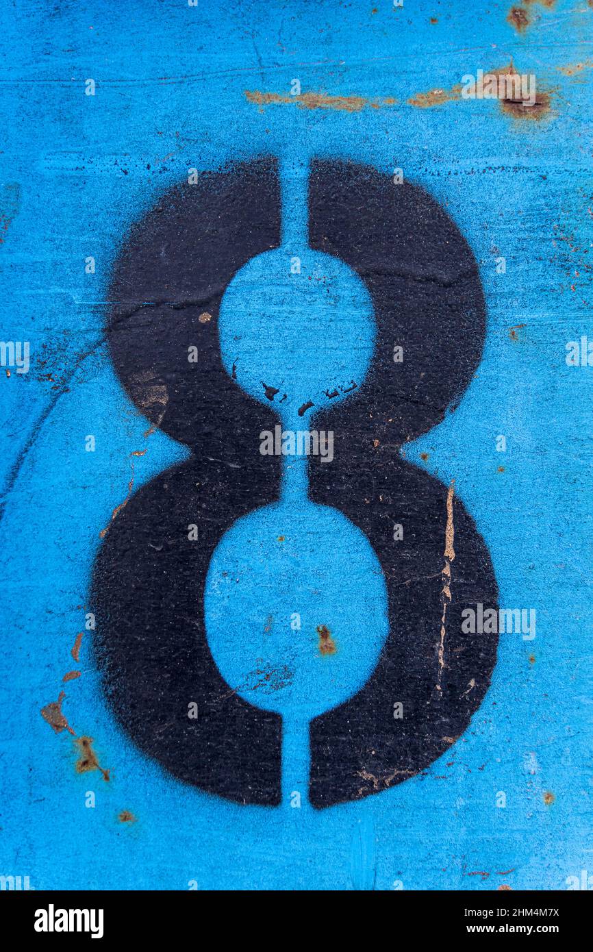 Number 8 in black paint on an old blue iron surface with rust texture ...