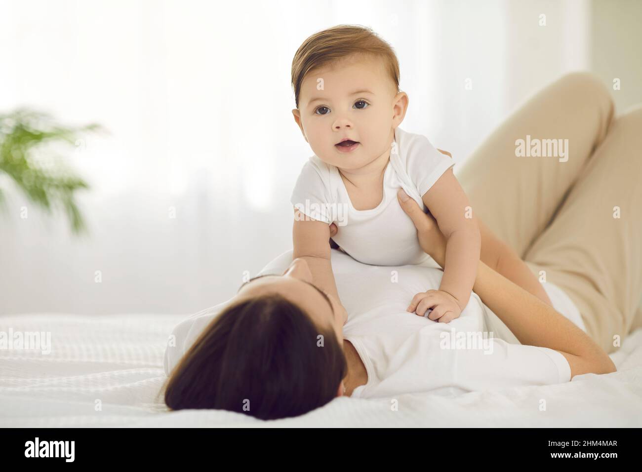 Happy adorable baby boy cuddling together with his mommy on comfortable ...