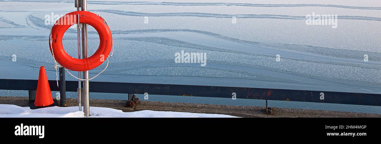 An orange lifesaver on the harbour with water surface texture of ...