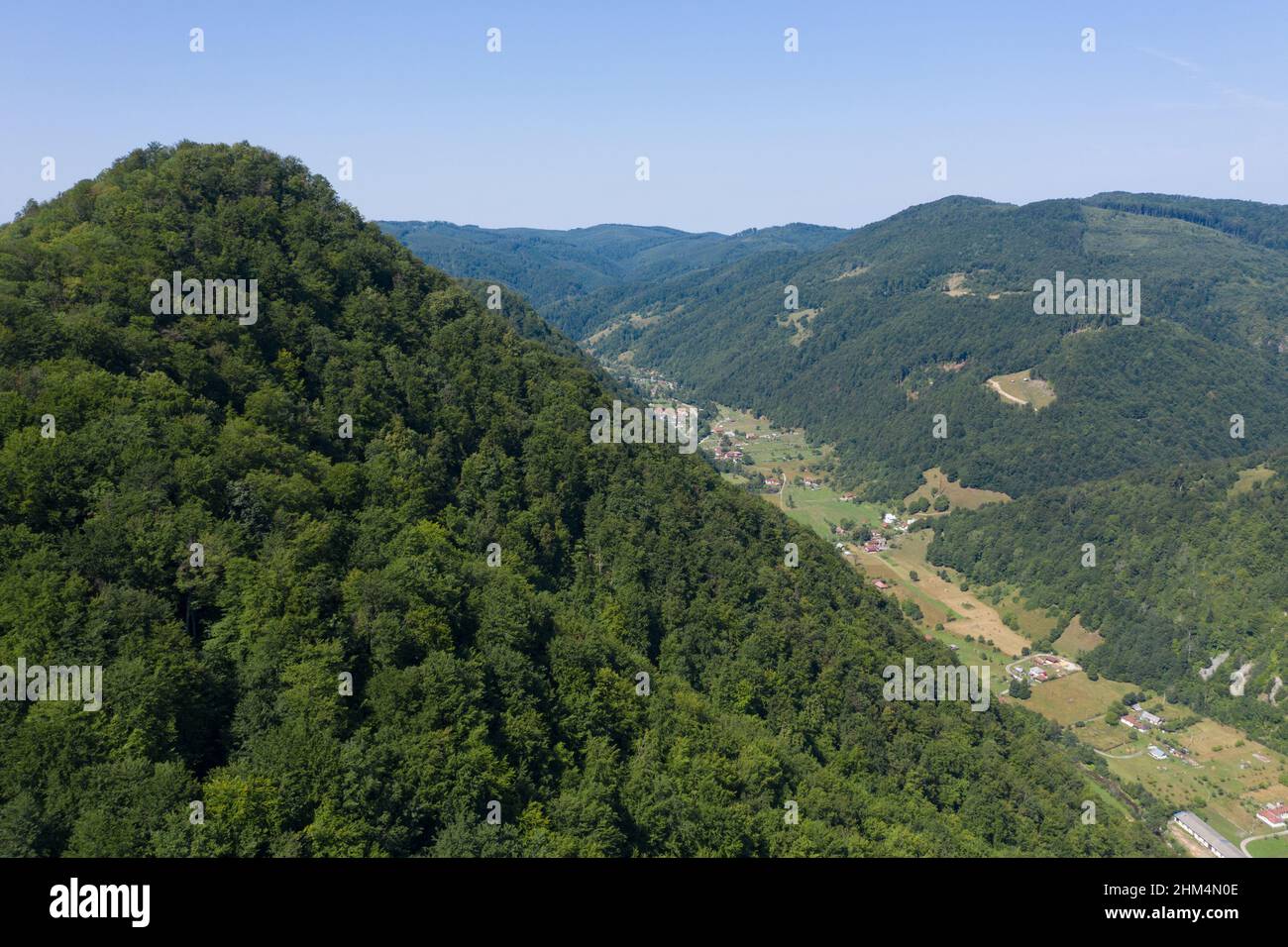 Flying above a deep valley and deciduous forest and limestone cliffs ...