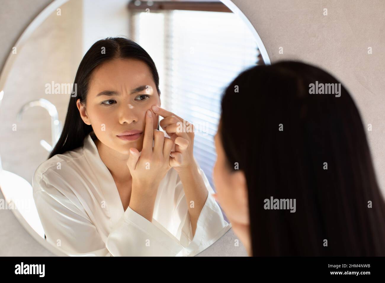 Upset chinese woman touching her face, pressing pimple Stock Photo - Alamy