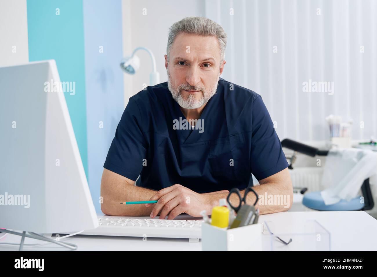 Serious physician sitting alone at desk in his office Stock Photo - Alamy