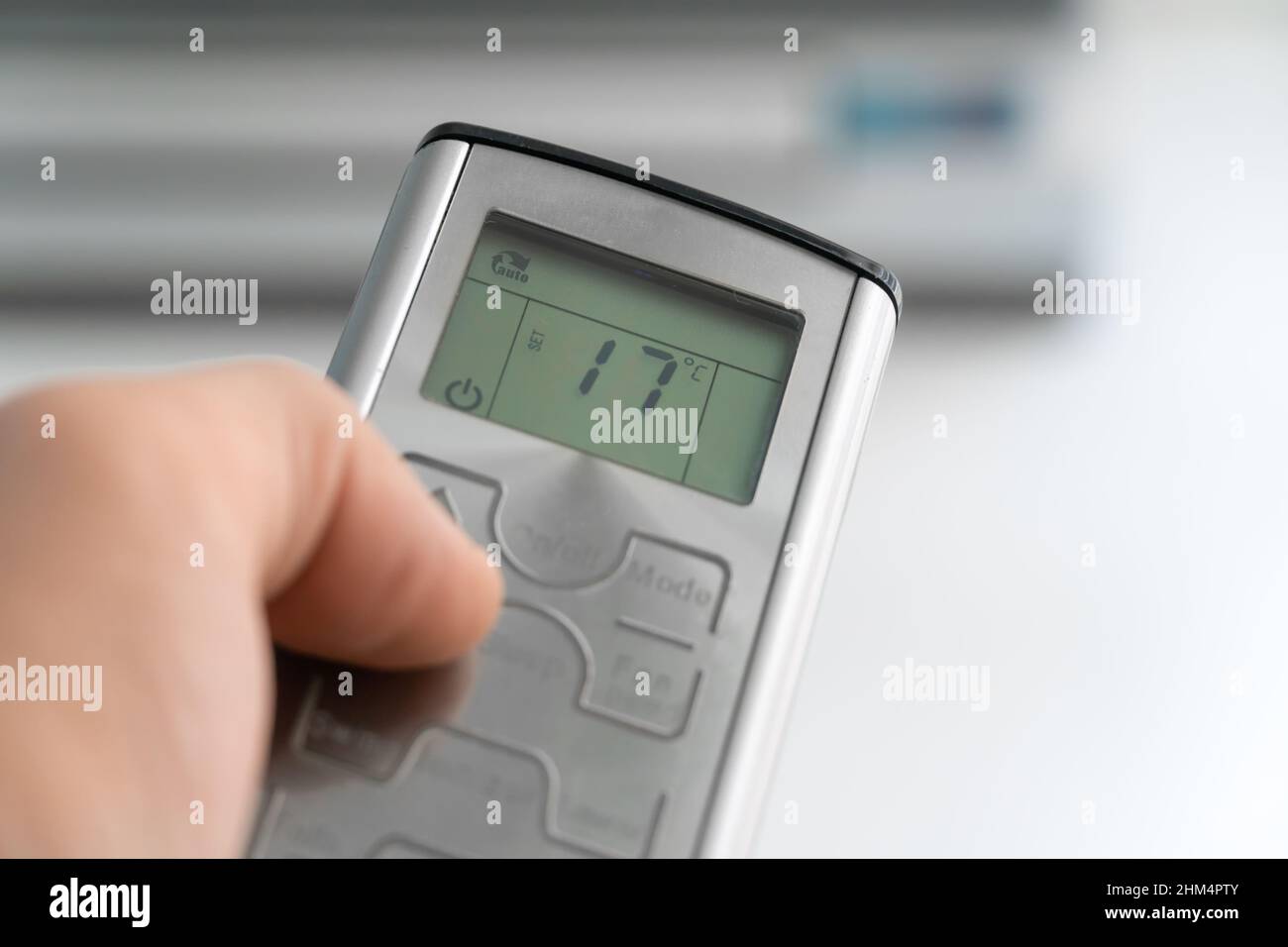 Close-up of a man's hand with a gray remote control pointing at the air ...