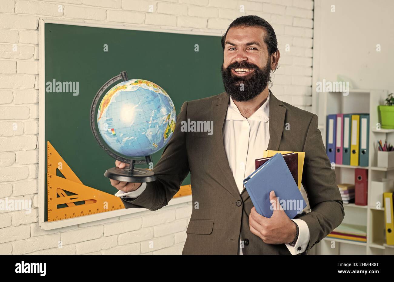 Portrait of a school teacher in academic classroom with globe ...