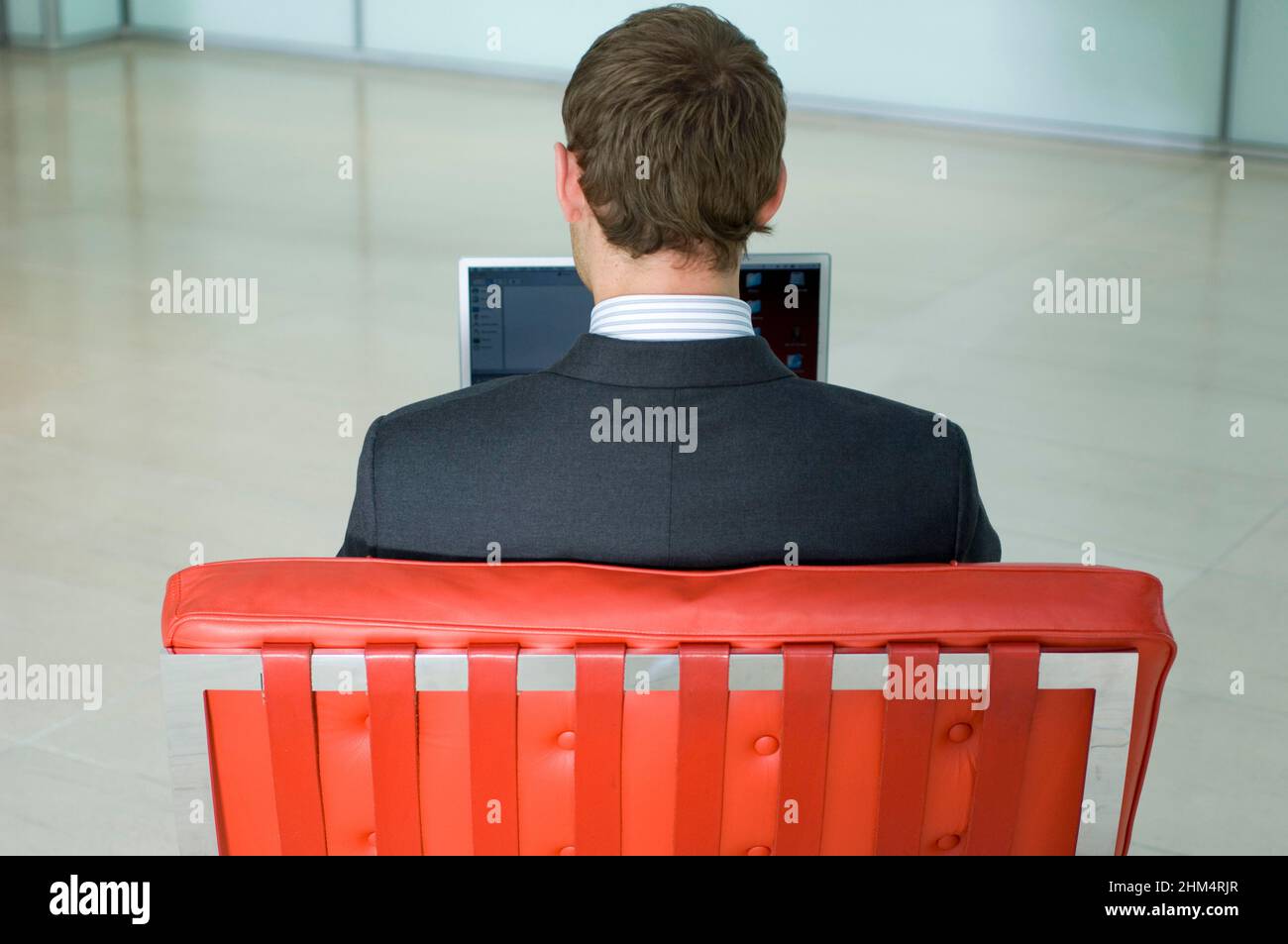 Rear View Of A Businessman Sitting On A Chair And Using A Laptop ...