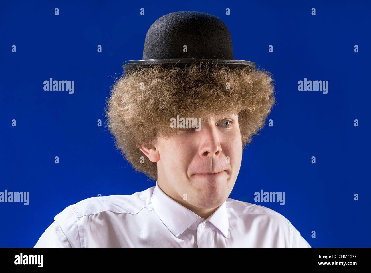Handsome curly man in a small hat. Humor. Cool guy. A funny student ...