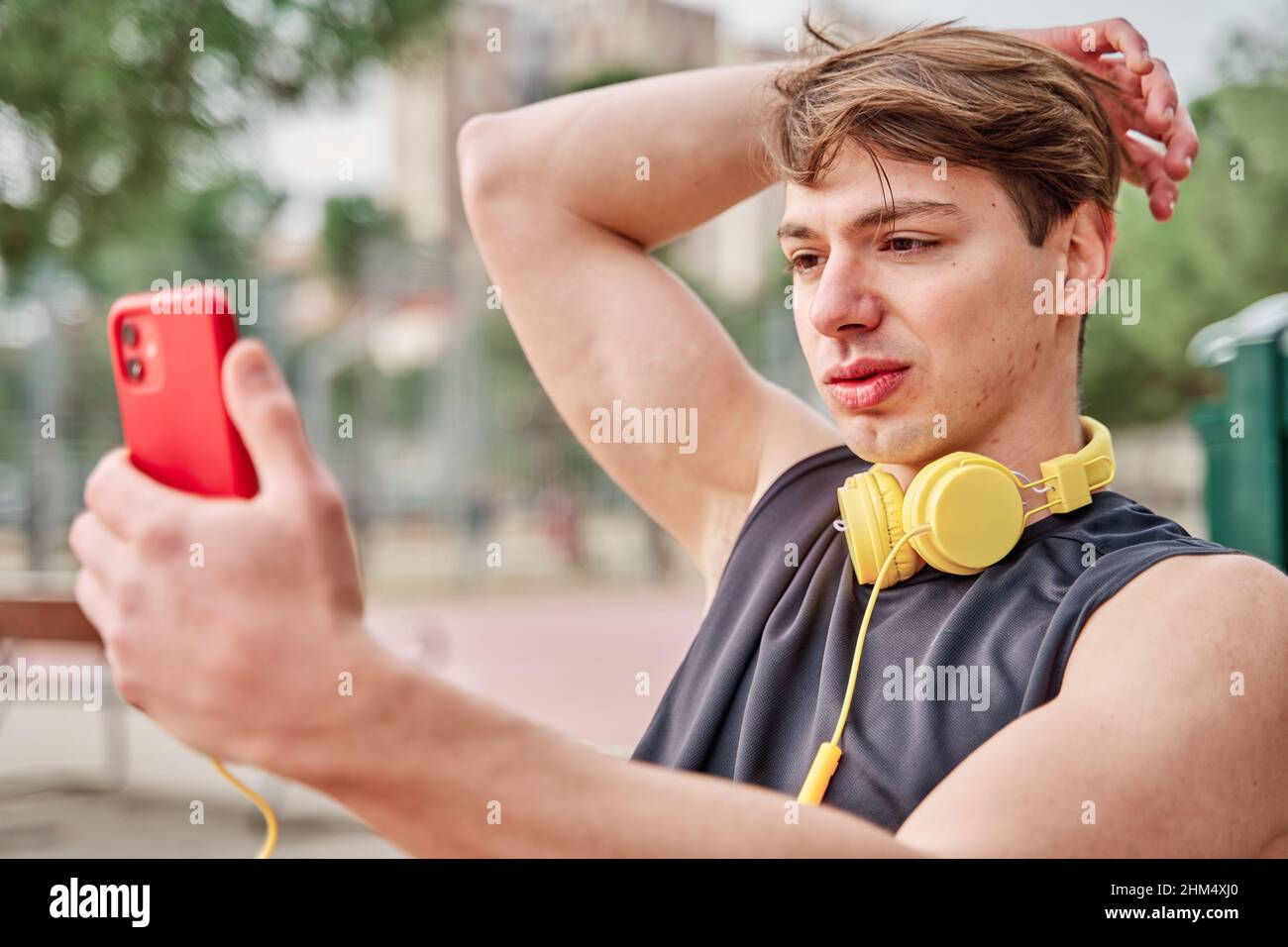 young athlete using mobile phone with headphones around his neck Stock ...