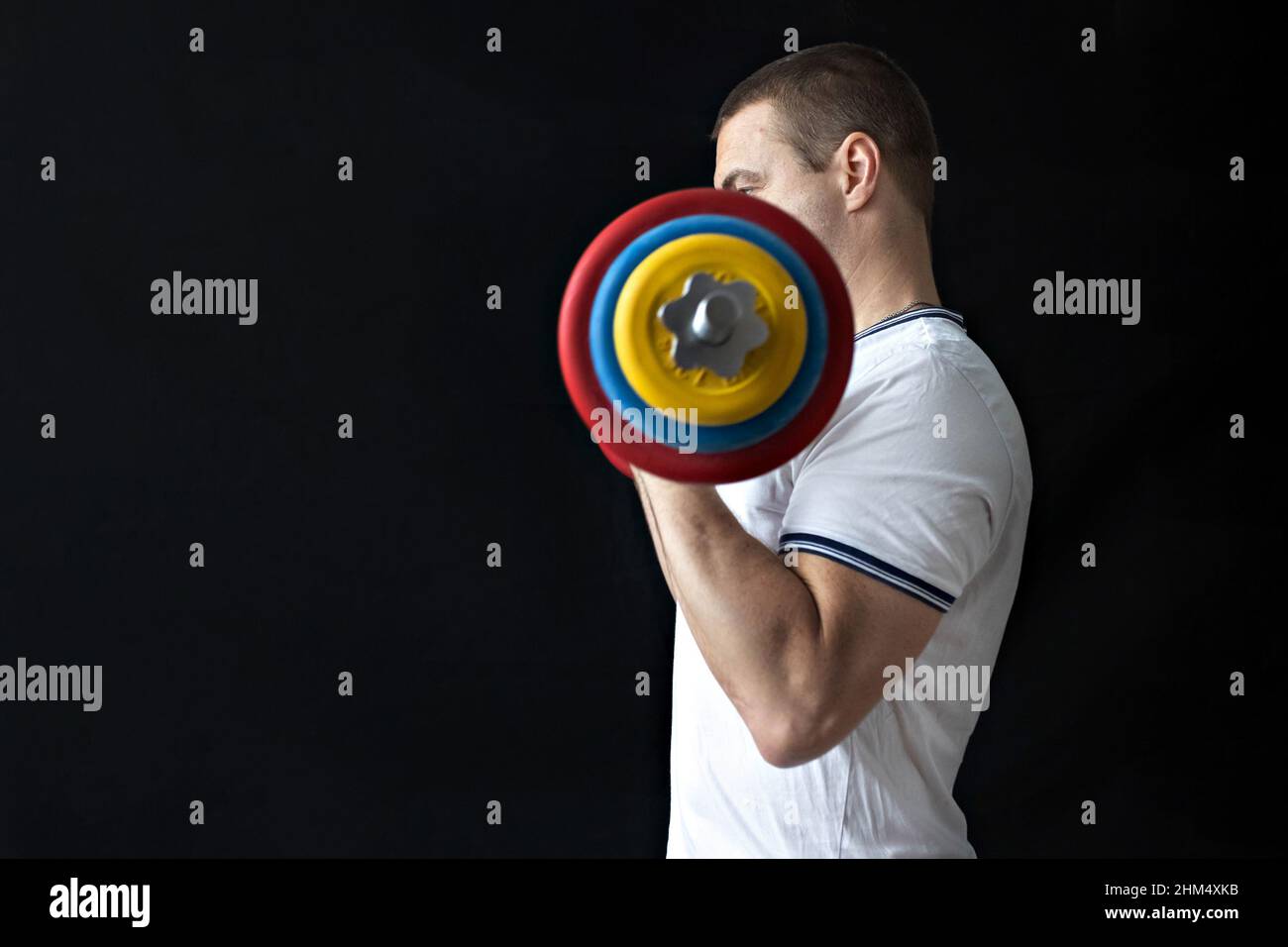 A strong, healthy man with muscles, training at home with a barbell ...