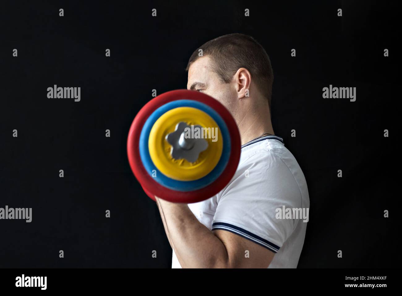 A strong, healthy man with muscles, training at home with a barbell ...