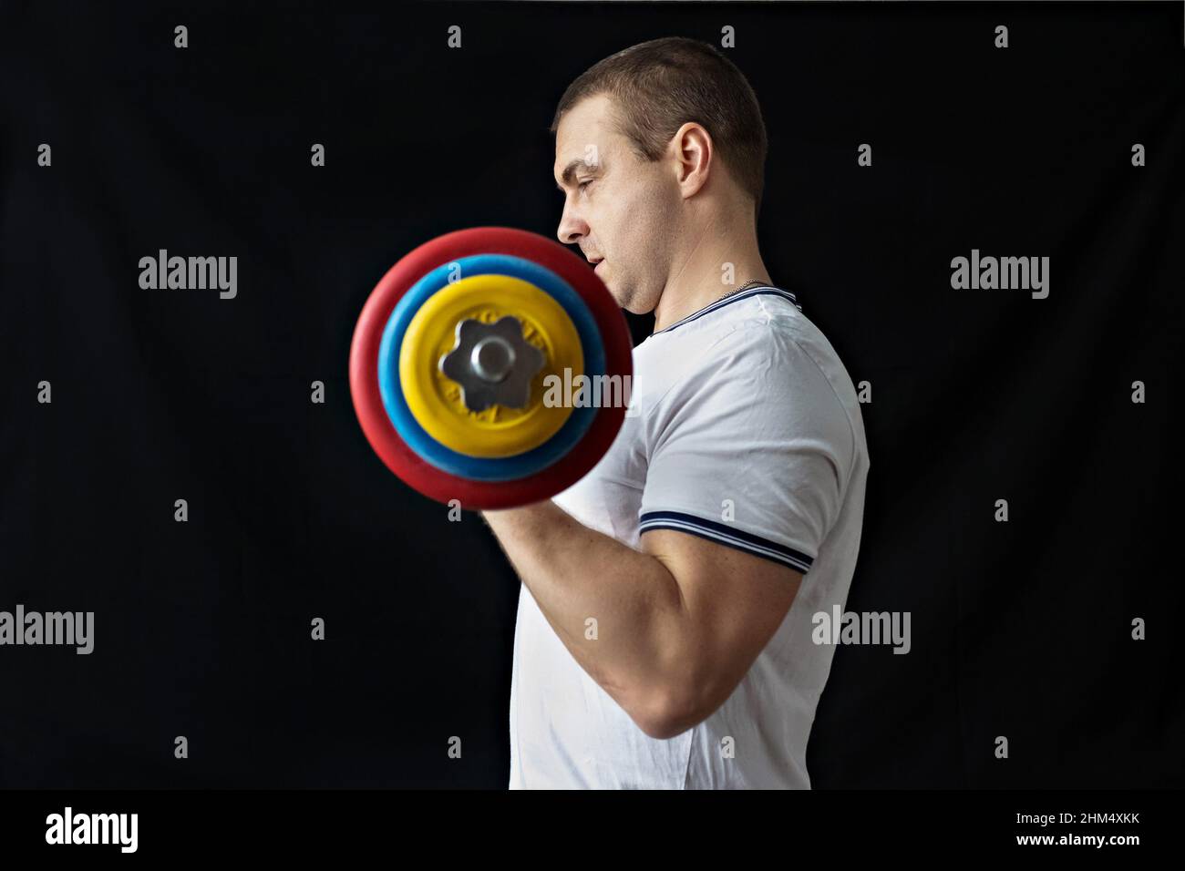 A strong, healthy man with muscles, training at home with a barbell ...