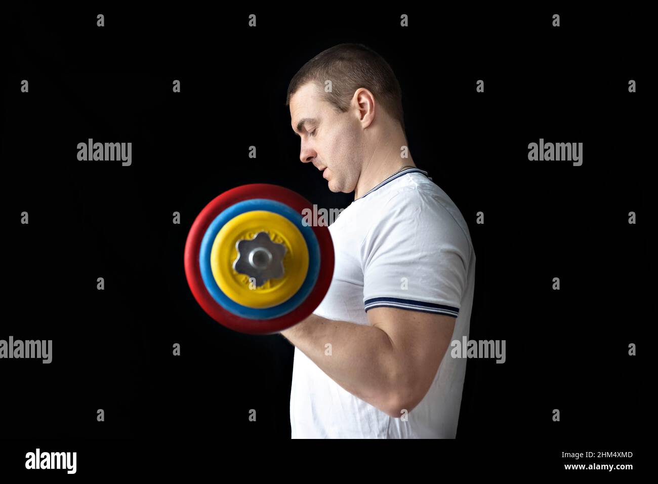 A strong, healthy man with muscles, training at home with a barbell ...