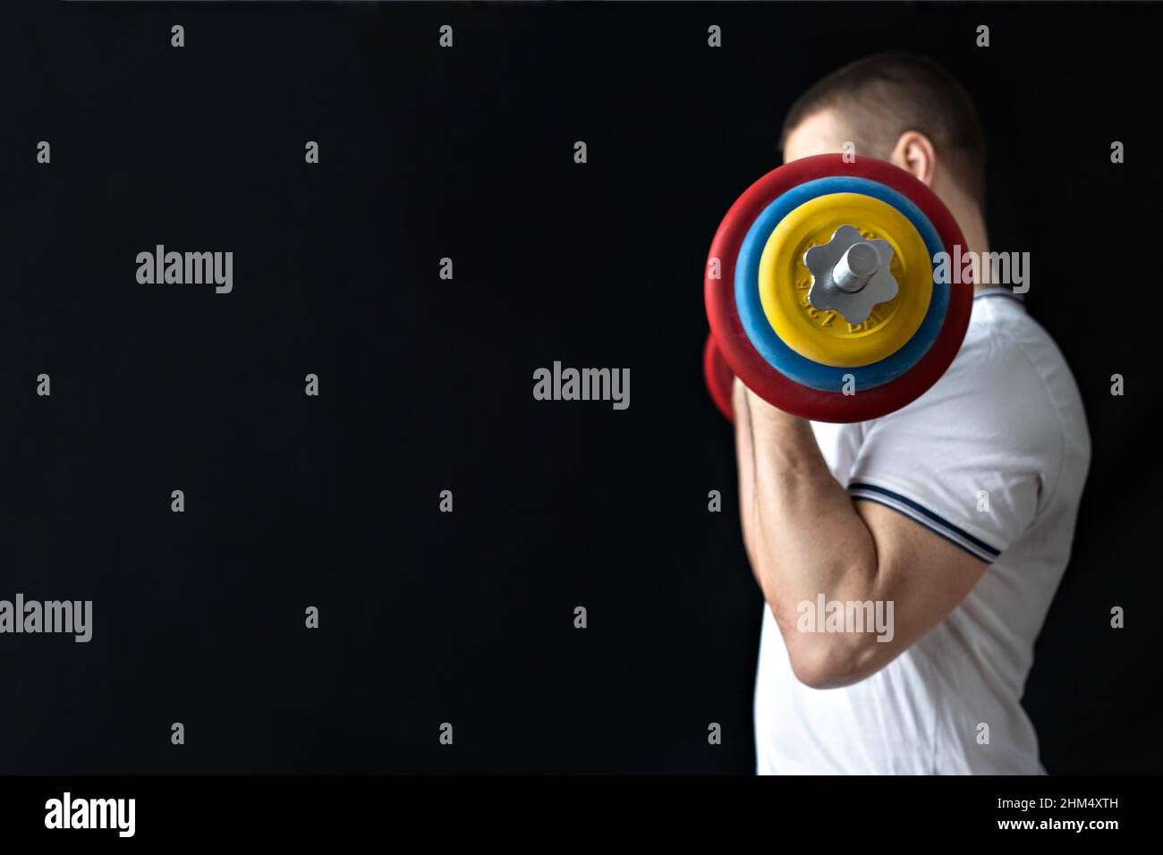 A strong, healthy man with muscles, training at home with a barbell ...