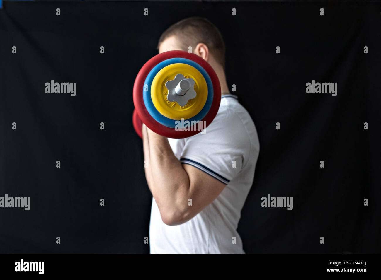 A strong, healthy man with muscles, training at home with a barbell ...
