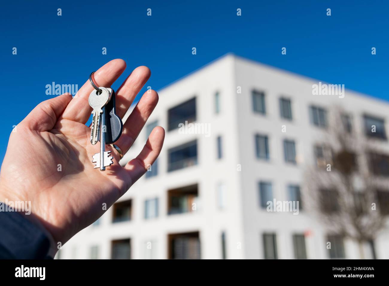 Hand holding keys in front of building Stock Photo - Alamy