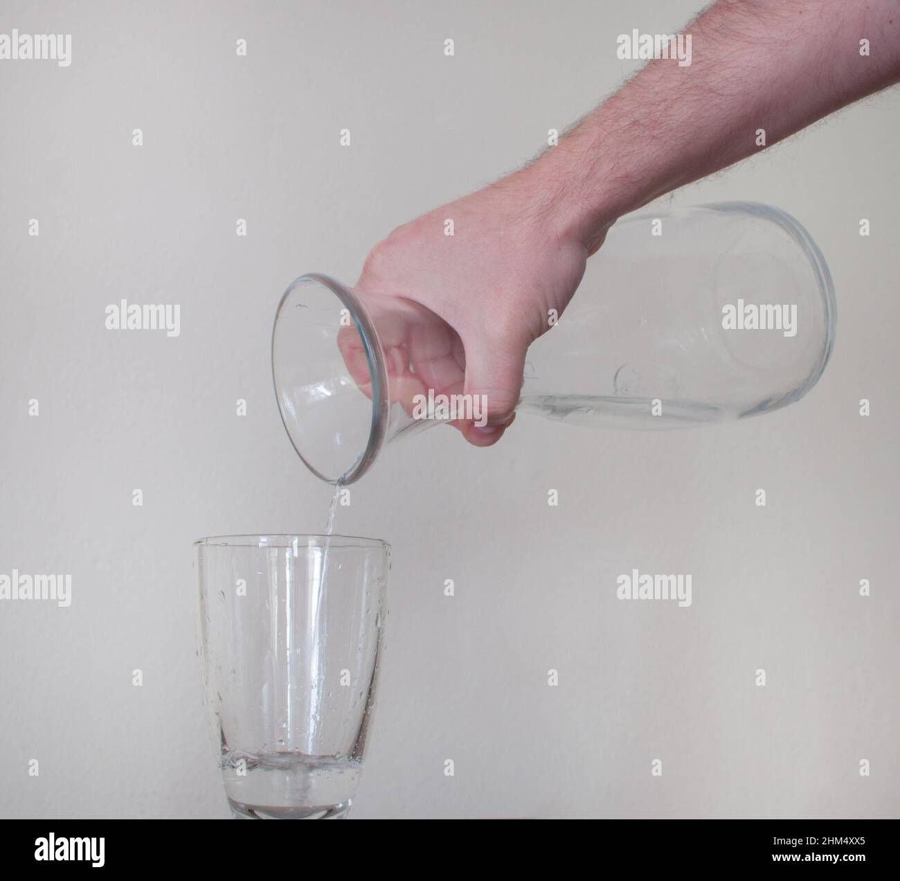 hand pours the last drops of water into a glass from a glass jug Stock ...