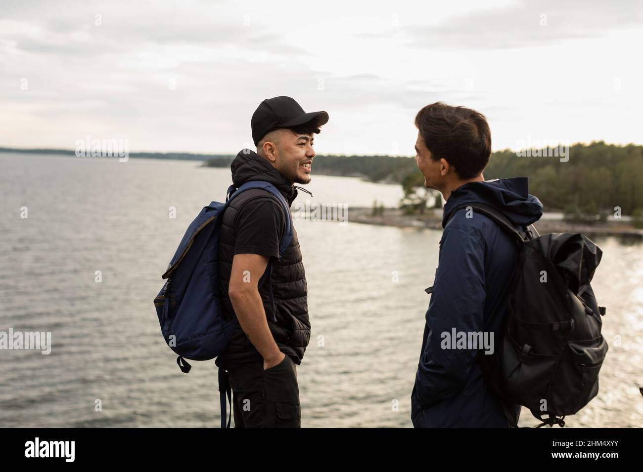 Smiling male friends talking at sea Stock Photo - Alamy