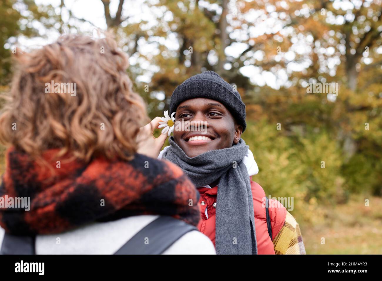 Woman putting flower behind friend's ear Stock Photo - Alamy