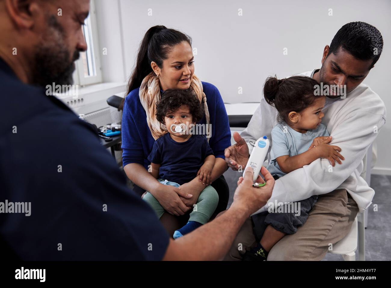 Male doctor examining family with children Stock Photo - Alamy