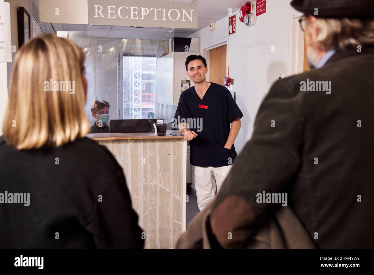 Patients and doctor at reception desk Stock Photo - Alamy