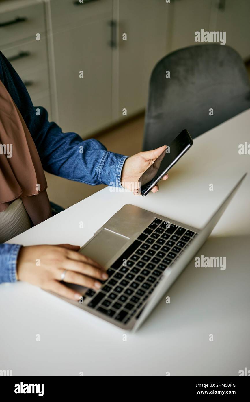 Woman's hands using cell phone and laptop Stock Photo - Alamy