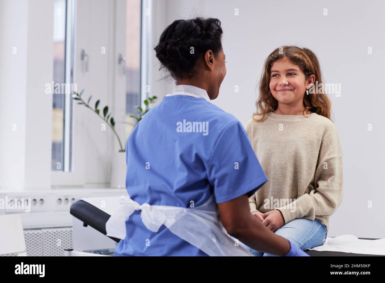 Female doctor talking to girl patient during appointment Stock Photo ...