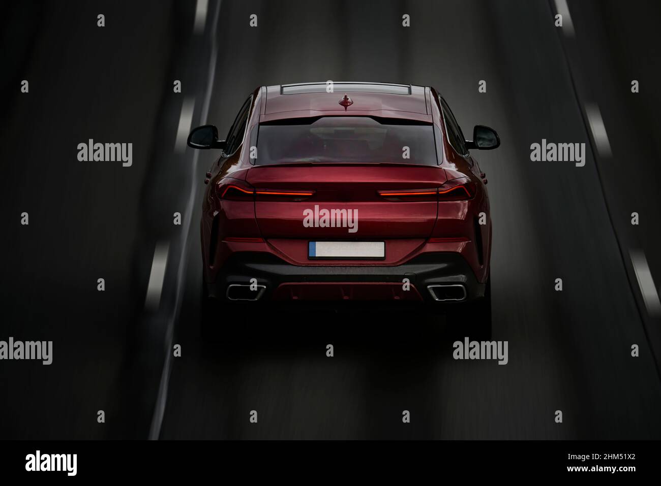 A red hatchback car driving fast on the countryside road with green ...