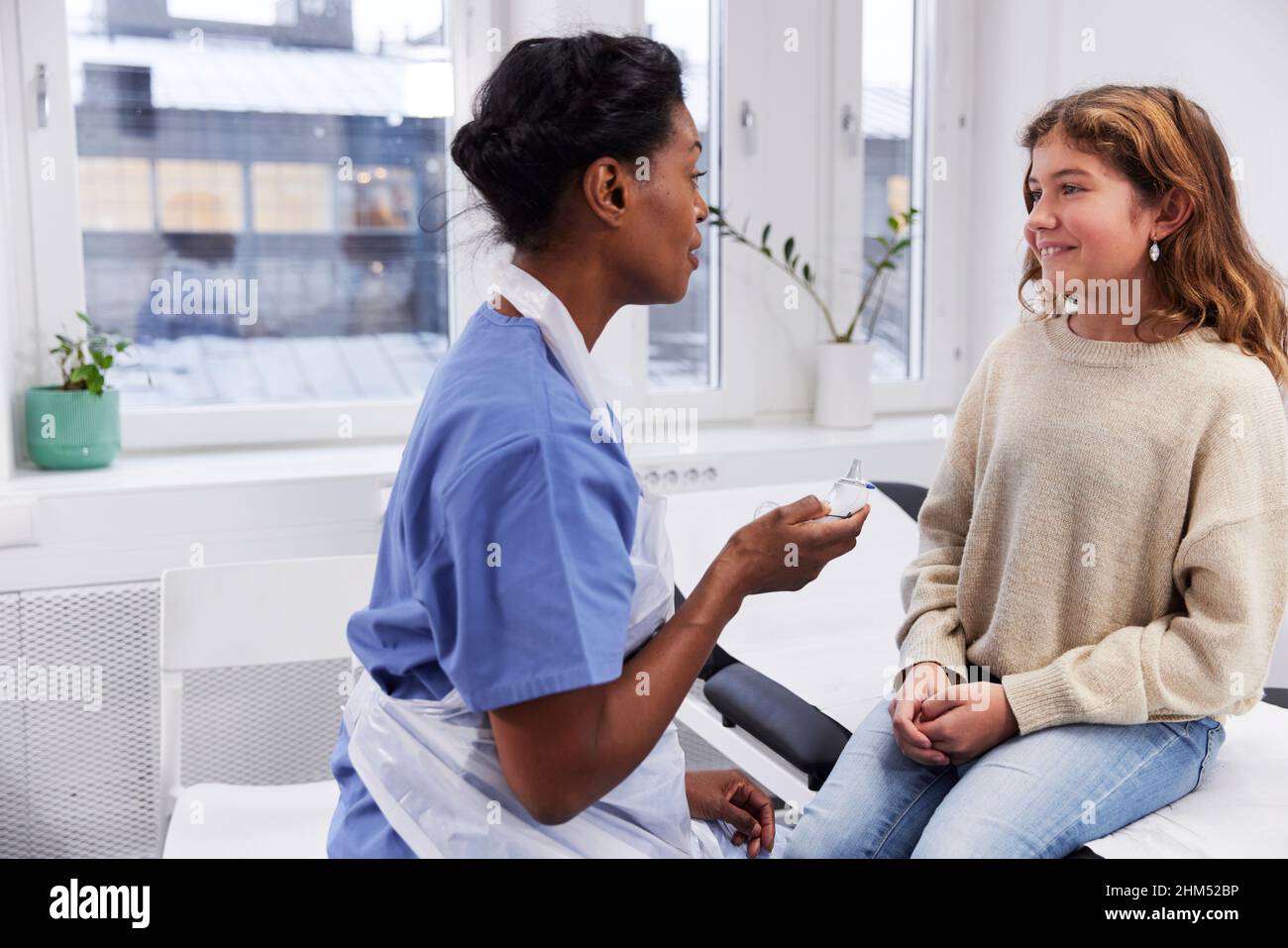Female doctor talking to girl patient during appointment Stock Photo ...