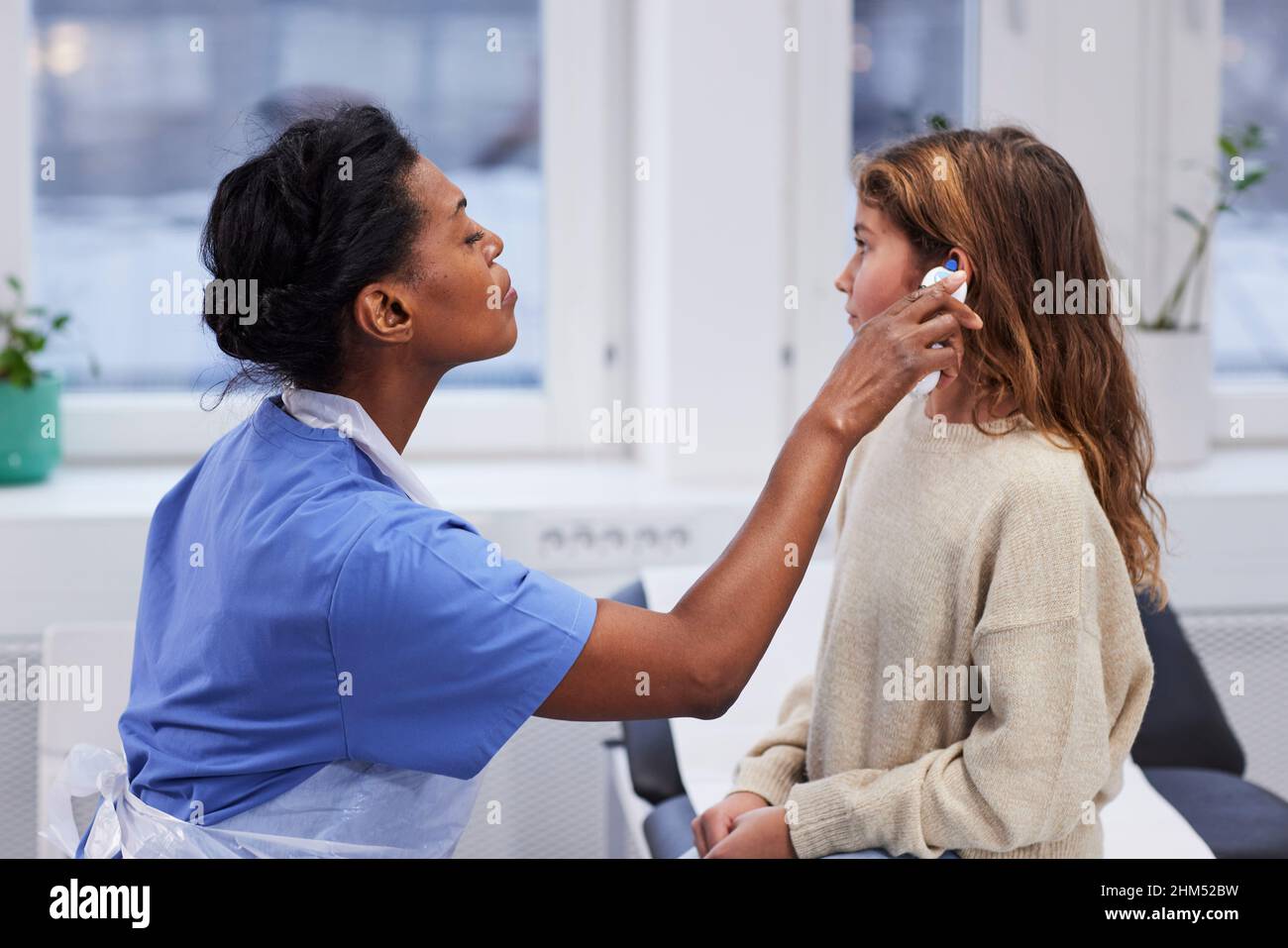 Female doctor examining girl patient's ear Stock Photo - Alamy