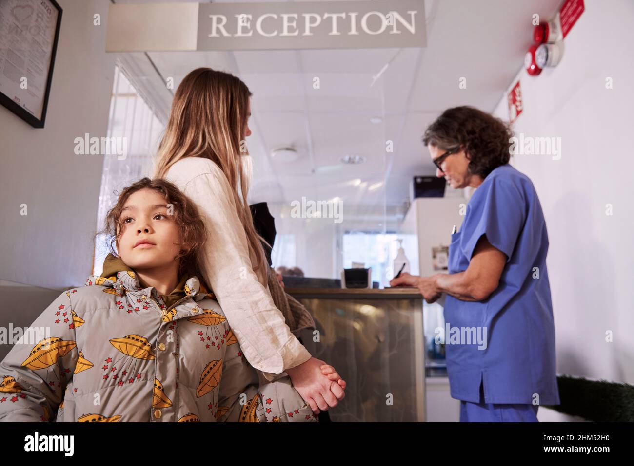 Female doctor with patients at reception desk Stock Photo - Alamy