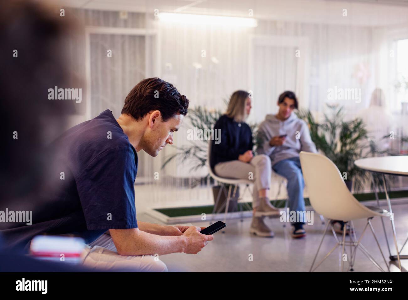 Man using smart phone in waiting room Stock Photo - Alamy