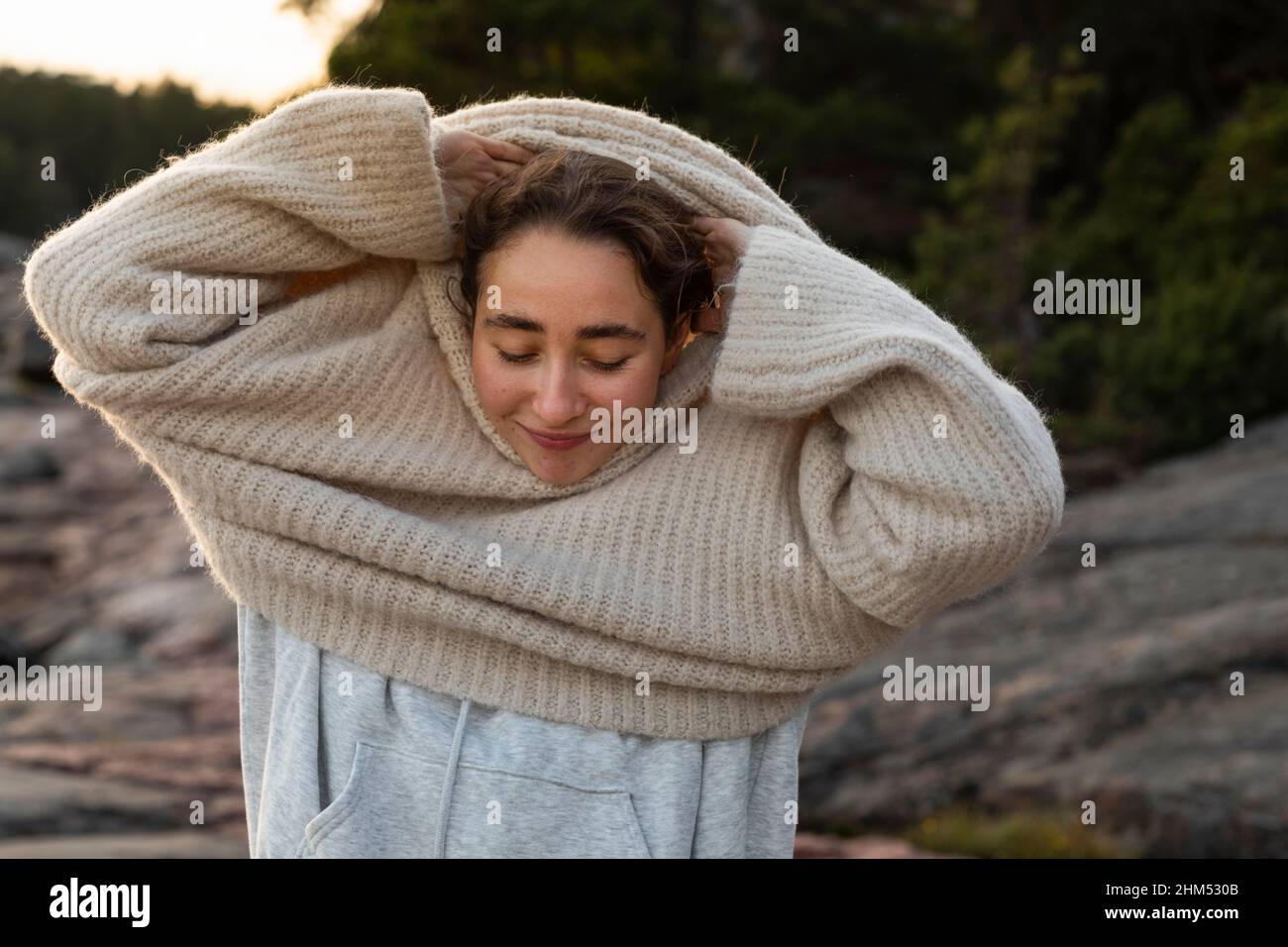 Woman putting jumper on Stock Photo - Alamy