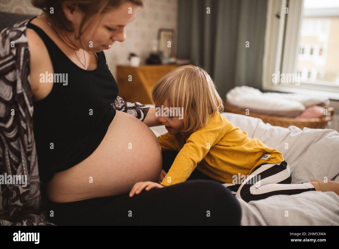 Girl talking to pregnant mother's belly Stock Photo - Alamy