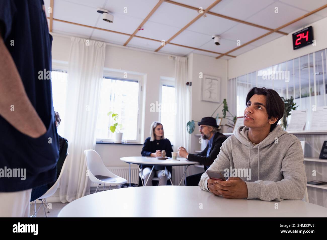 Patients sitting at tables in waiting room Stock Photo - Alamy
