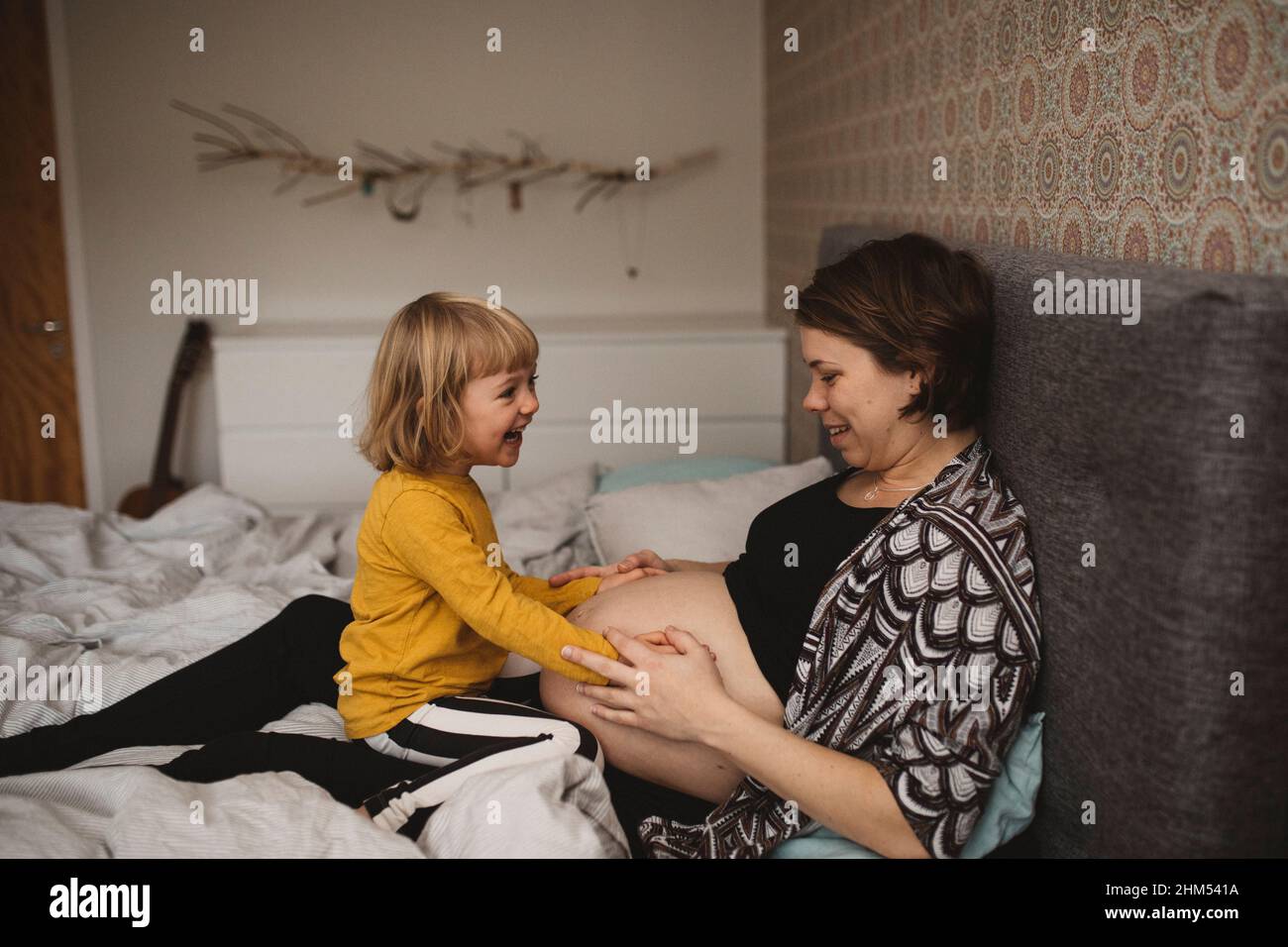 Pregnant woman and daughter touching belly Stock Photo - Alamy