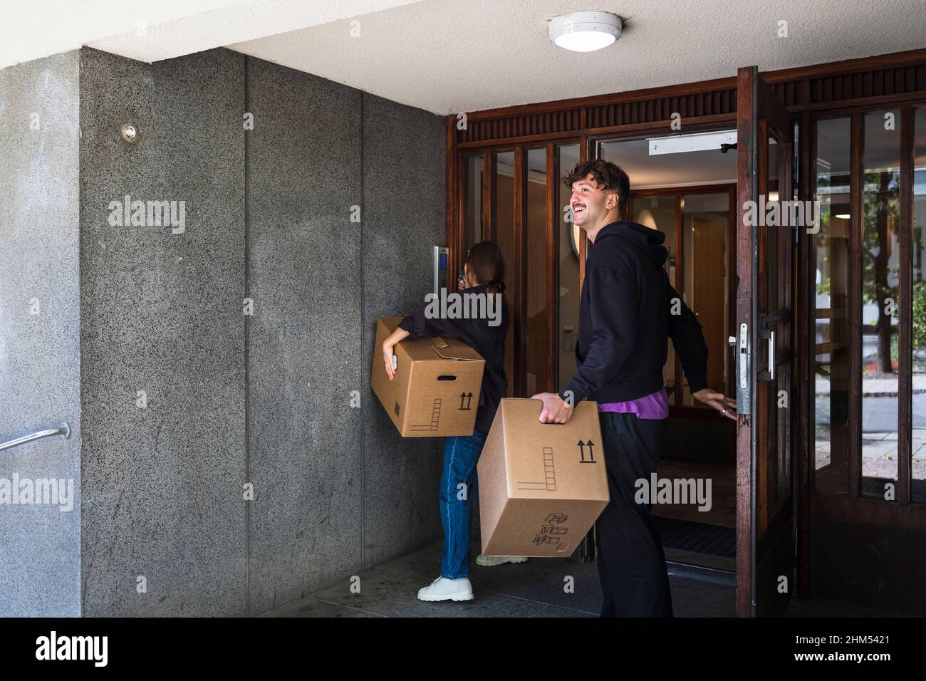 Couple entering building carrying boxes Stock Photo - Alamy