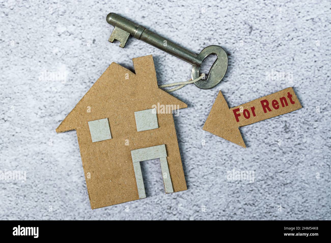 For rent text on brown arrow and paper house model with key on floor ...