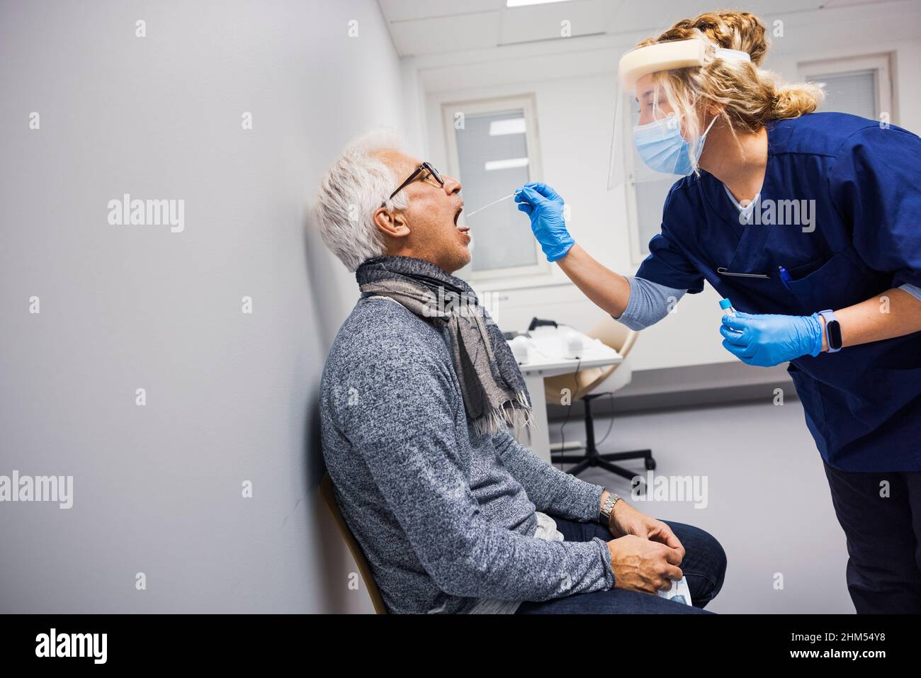 Female doctor performing covid-19 swab test on senior man Stock Photo ...