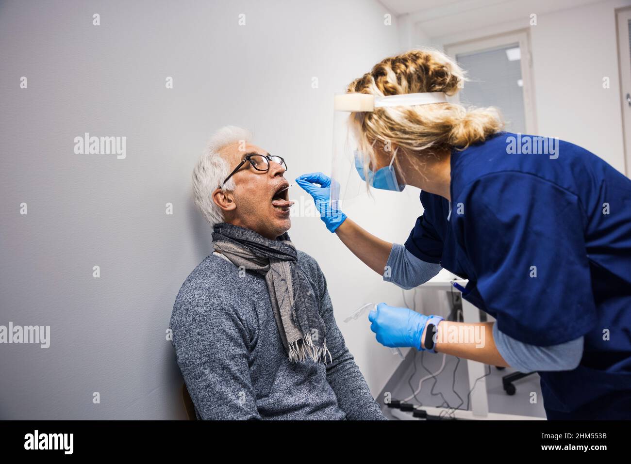Female doctor performing covid-19 swab test on senior man Stock Photo ...