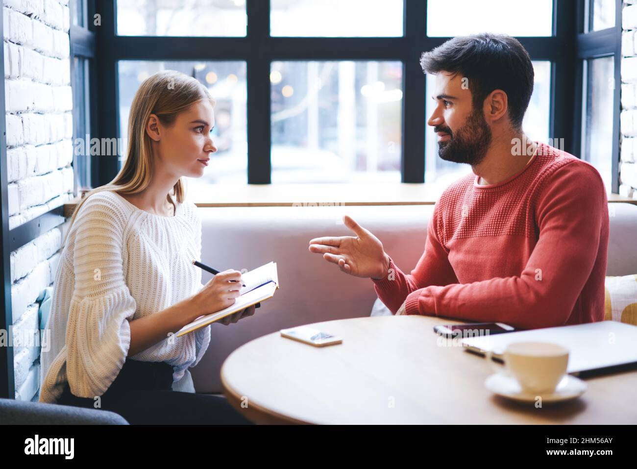 Serious young colleague writing notes during coworker speech Stock ...