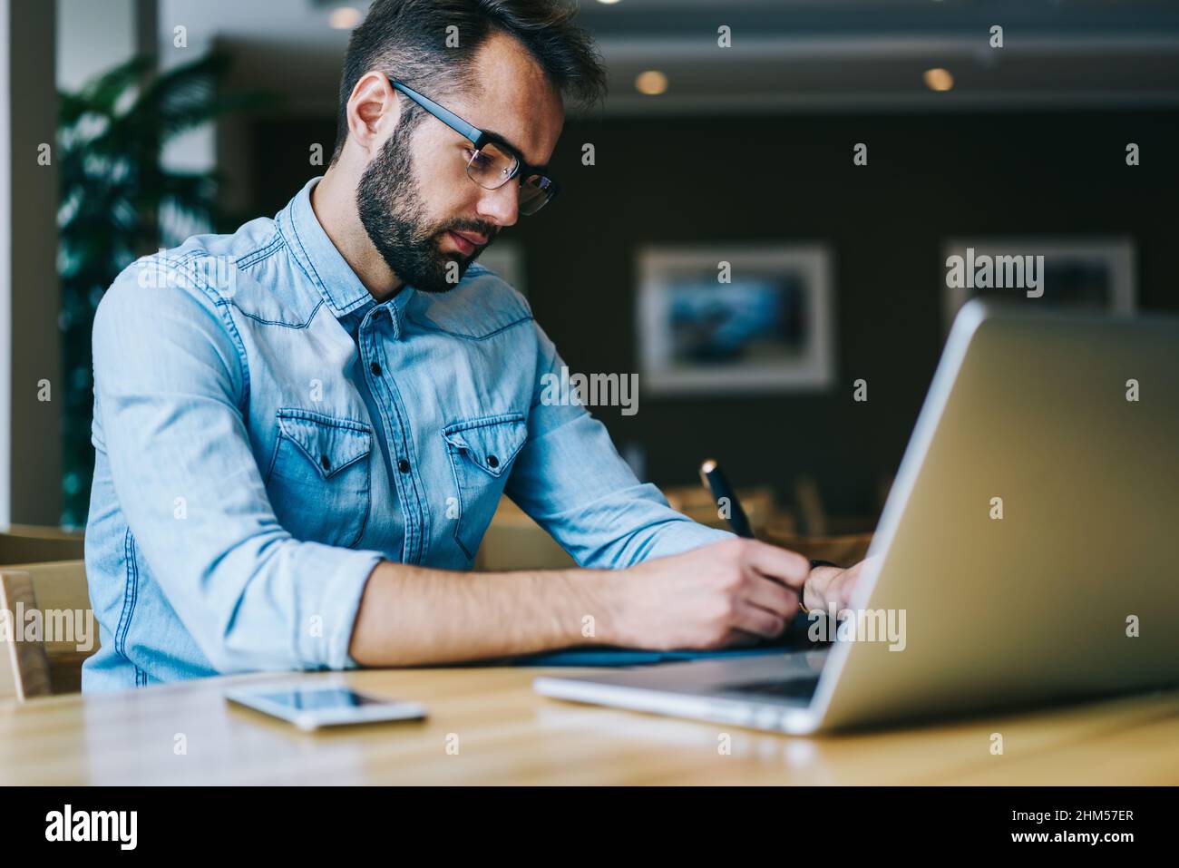 Serious man taking notes while working Stock Photo - Alamy