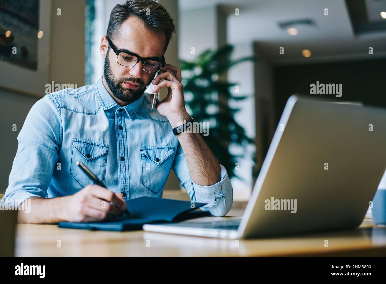 Serious man talking on phone and taking notes Stock Photo - Alamy