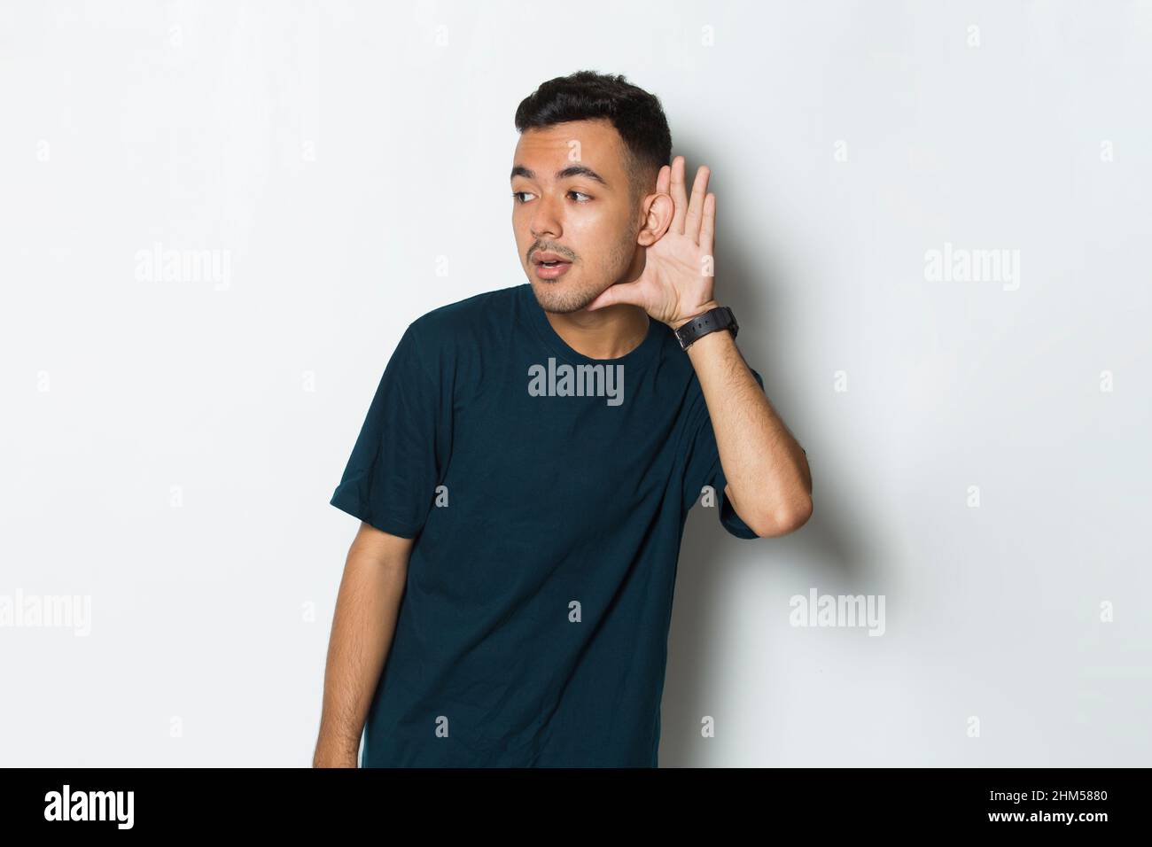 Young handsome man with hand over ear listening an hearing to gossip ...