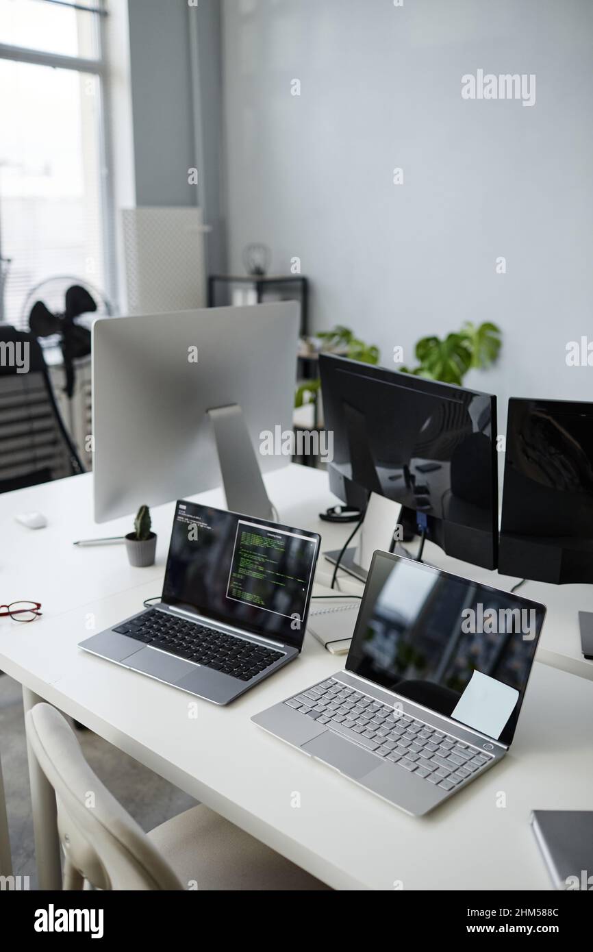 Part of openspace office with group of laptops and computer monitors on ...