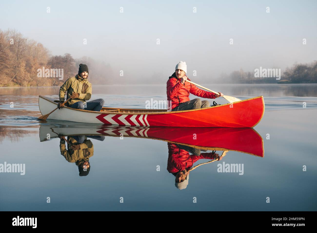 Two men paddling in a wooden canoe on a lake with still water Stock ...