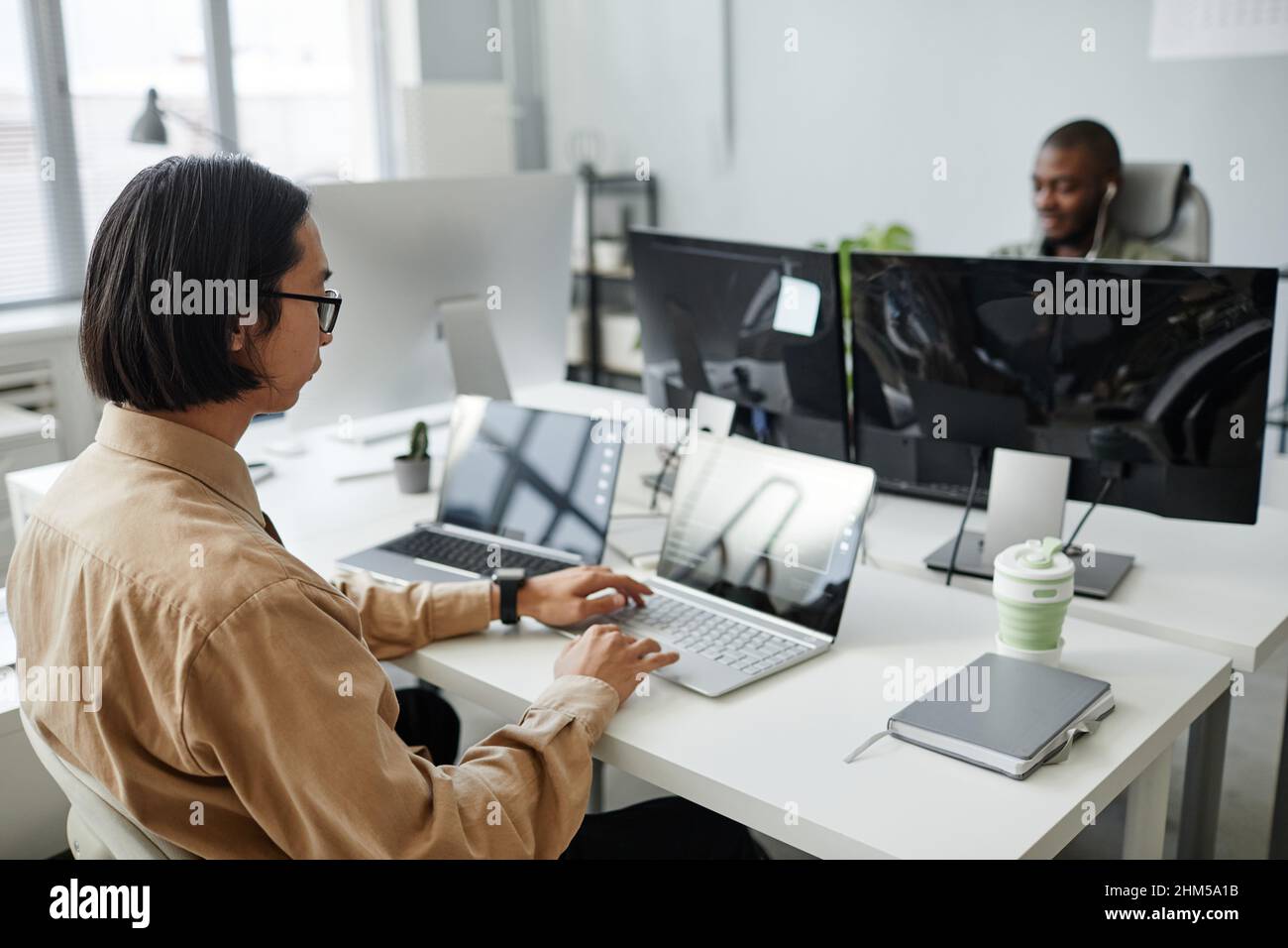Young Asian male programmer looking at decoded data on laptop screen ...