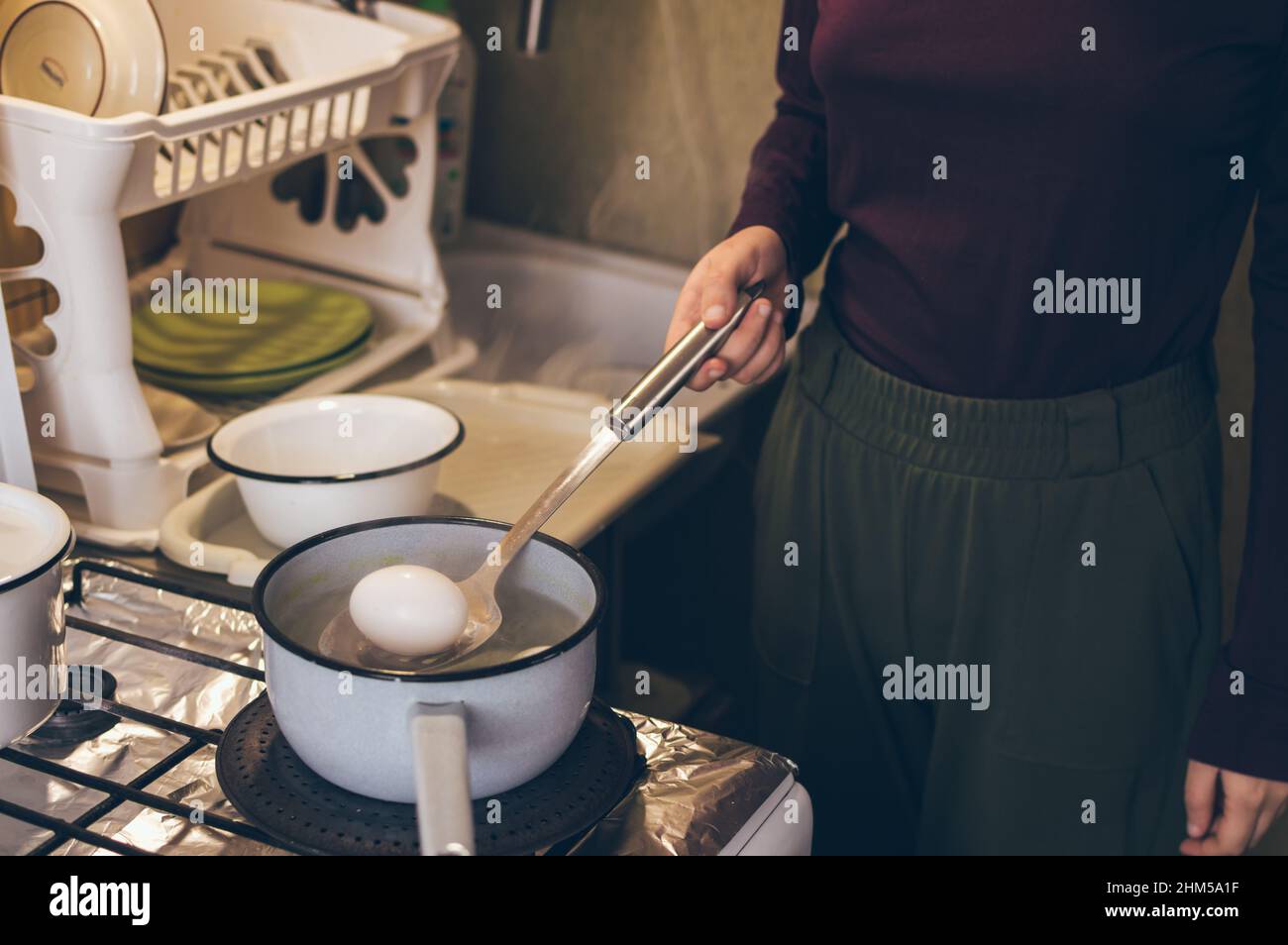 Cooking eggs in enameled ladle for coloring for easter Stock Photo - Alamy